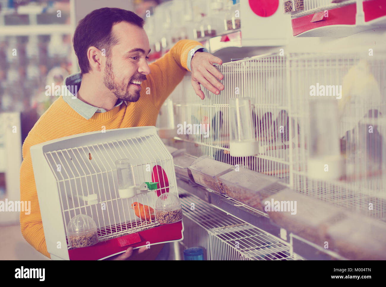 Happy positive male customer boasting his purchase of canary bird in ...