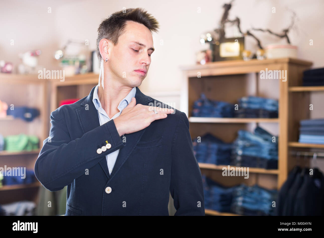 Positive guy shopper choosing new suit in men’s store Stock Photo - Alamy