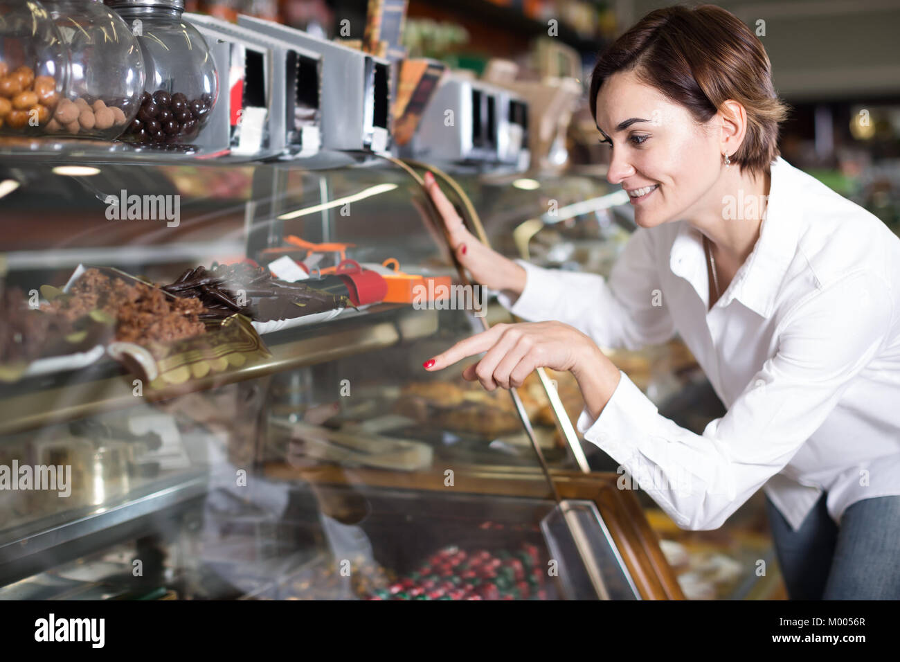 Female client choosing delicious dessert in confectionery Stock Photo ...