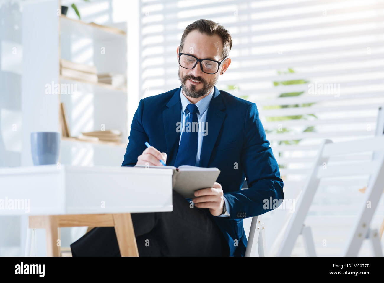 Meditative joyful man writing down agenda Stock Photo - Alamy