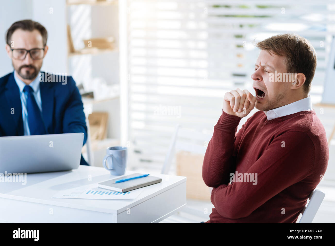 Young male colleague getting bored Stock Photo - Alamy