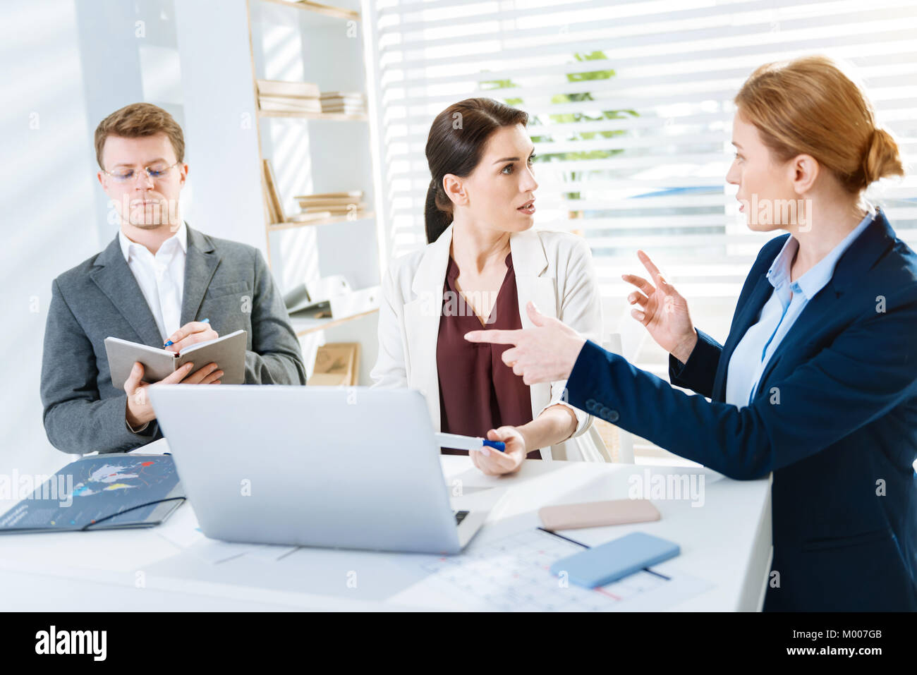 Attractive three colleagues arguing over issue Stock Photo - Alamy