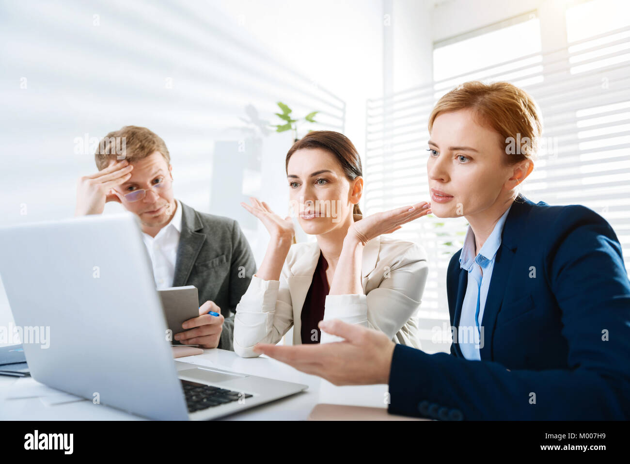 Concerned three colleagues calculating looses Stock Photo - Alamy