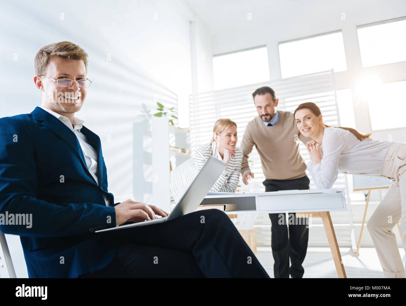 Happy male colleague using laptop Stock Photo - Alamy