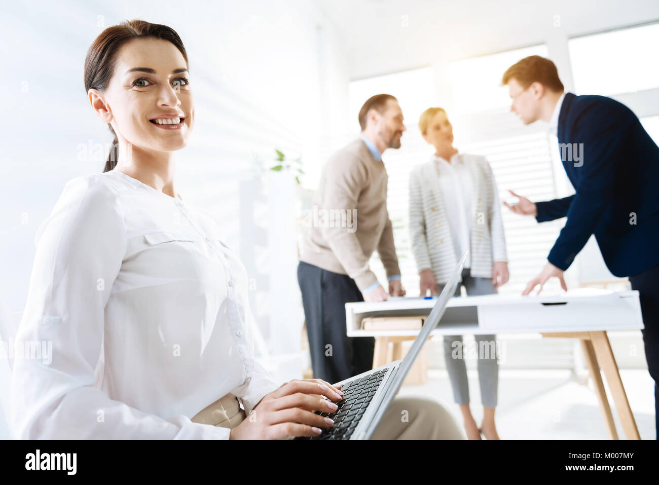 Attractive female colleague working with laptop Stock Photo - Alamy