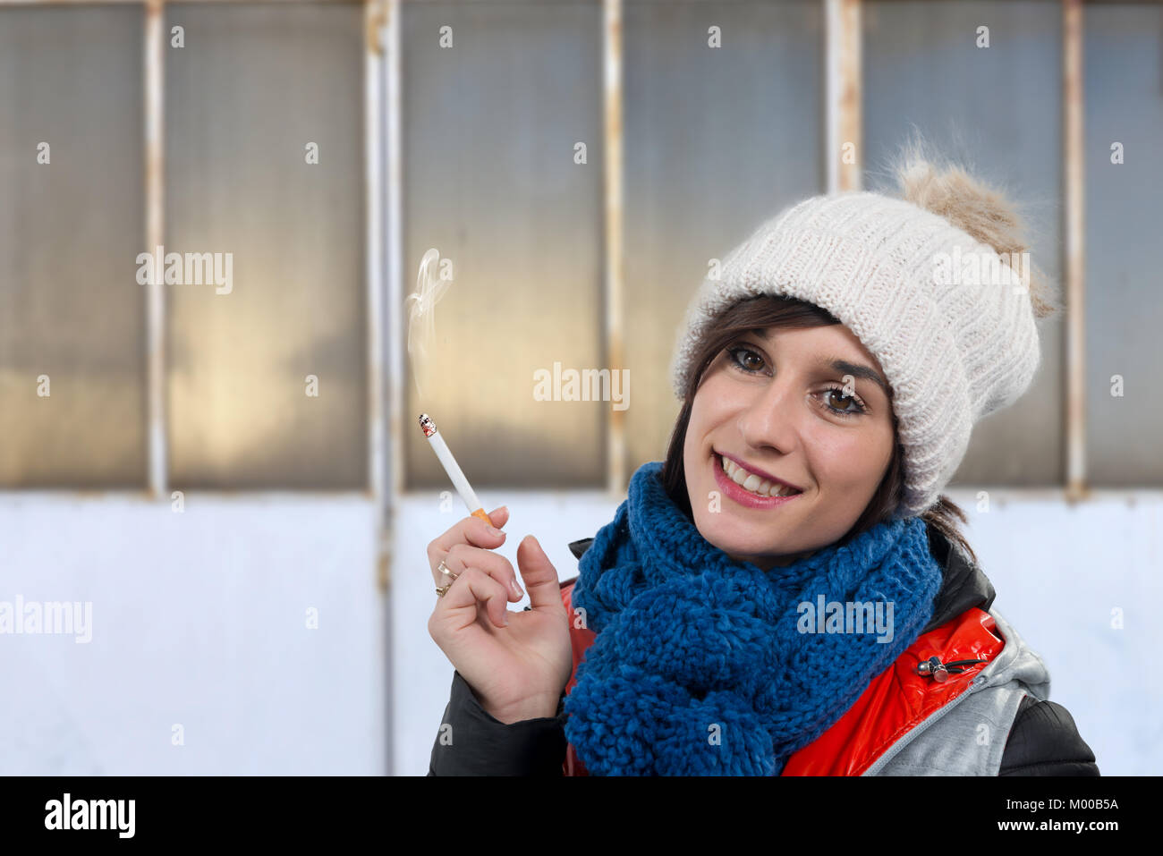 a young woman with winter cap smoking a cigarette Stock Photo - Alamy