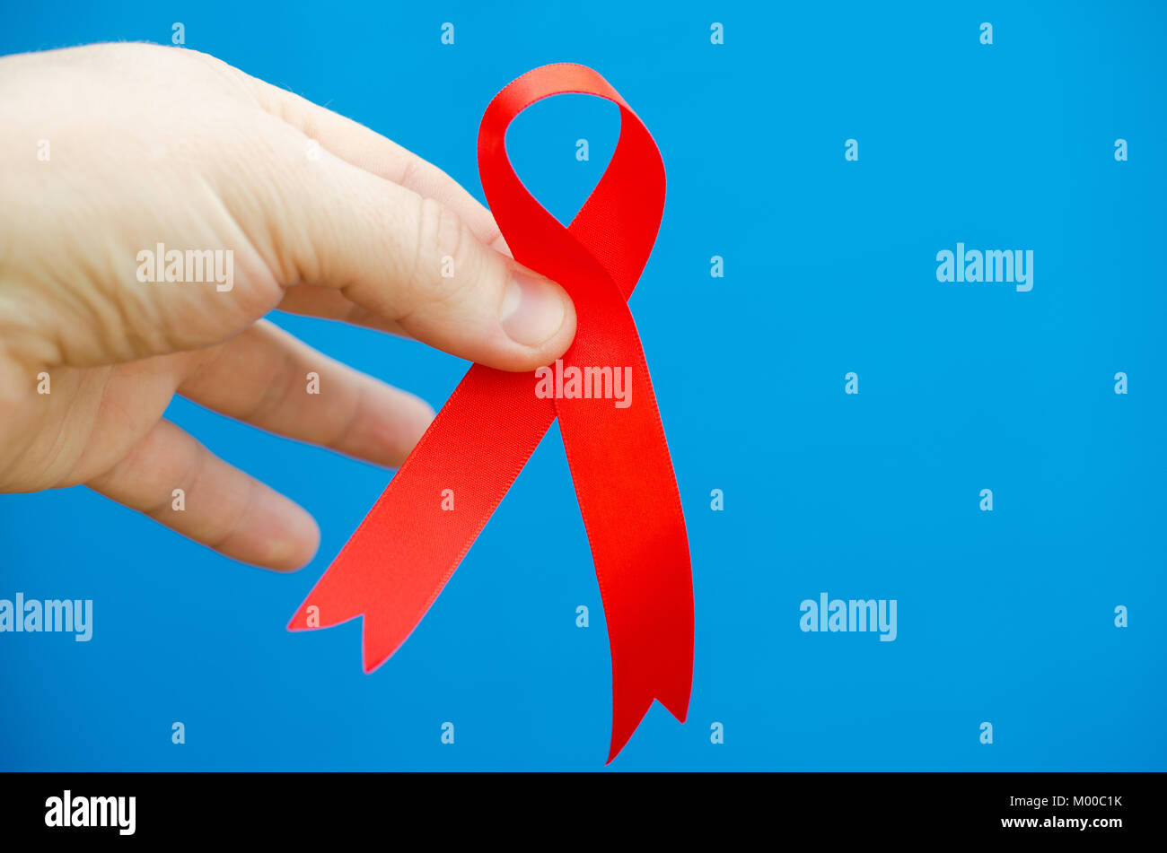 Red folded ribbon in hand on a blue background as a symbol of ...
