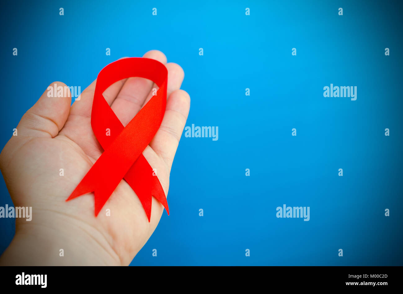 Red folded ribbon in hand on a blue background as a symbol of ...