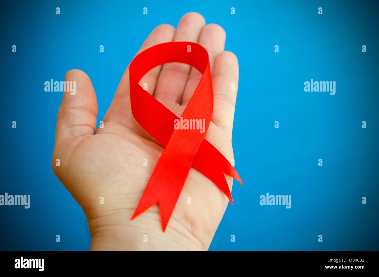 Red folded ribbon in hand on a blue background as a symbol of ...