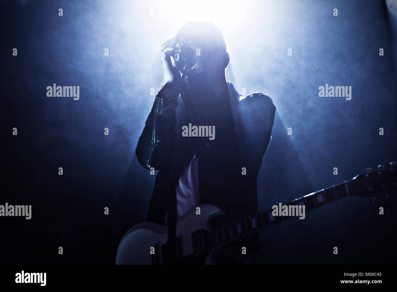A rock singer in classical leather jacket and with his guitar hanging ...