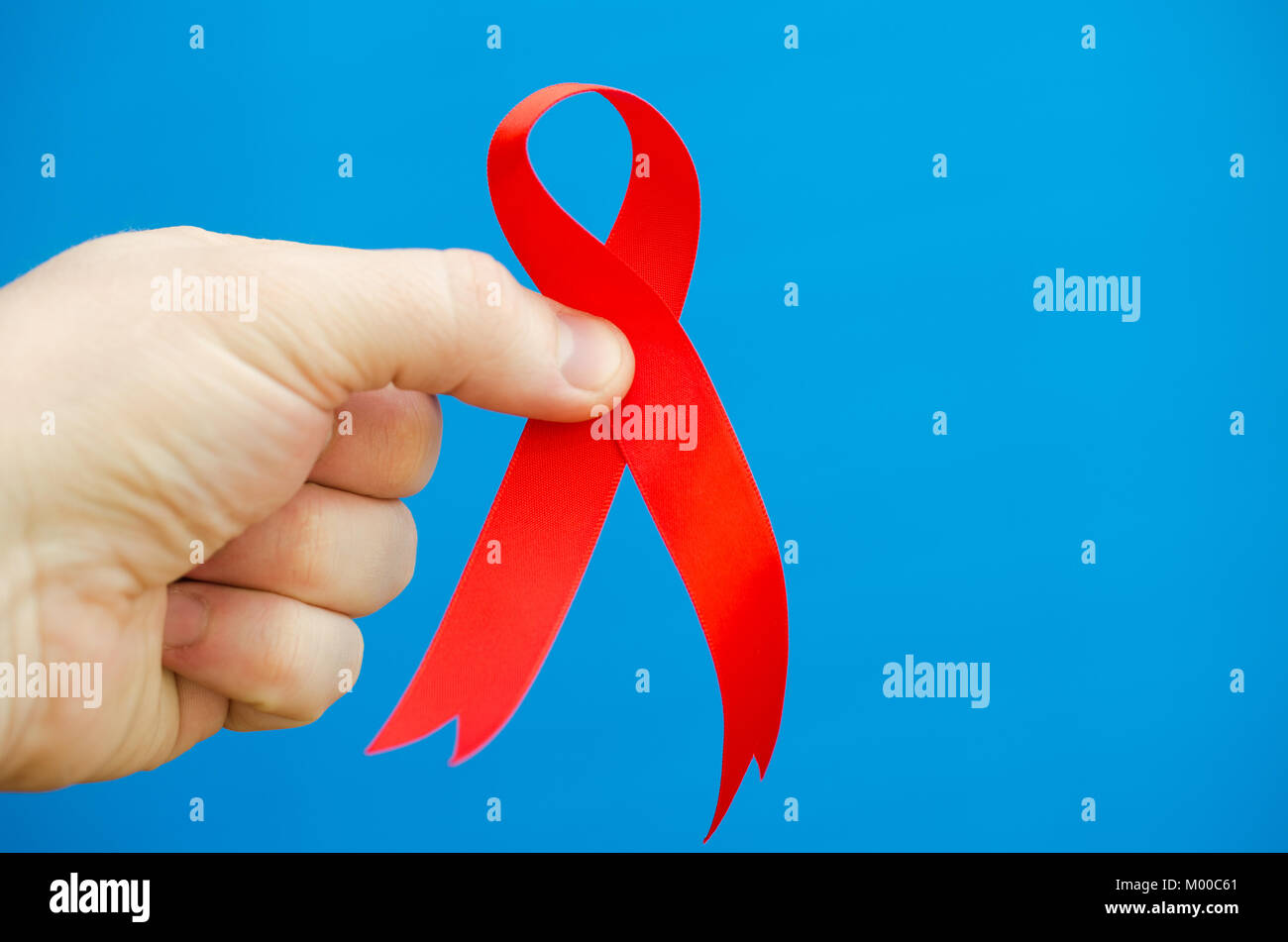 Red folded ribbon in hand on a blue background as a symbol of ...