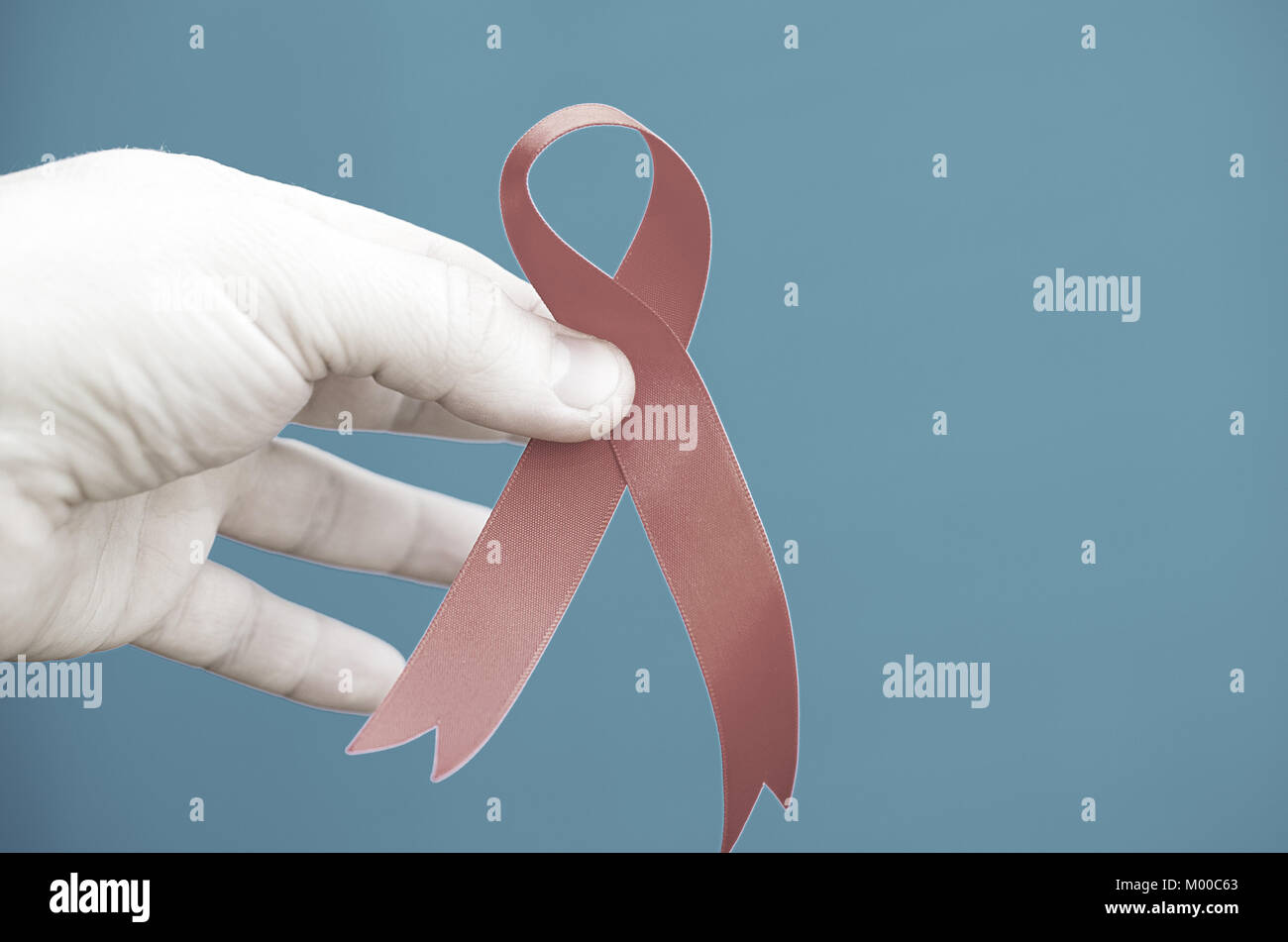 Red folded ribbon in hand on a blue background as a symbol of ...