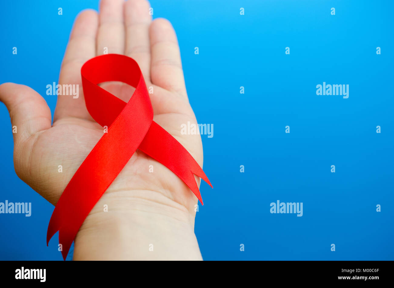Red folded ribbon in hand on a blue background as a symbol of ...