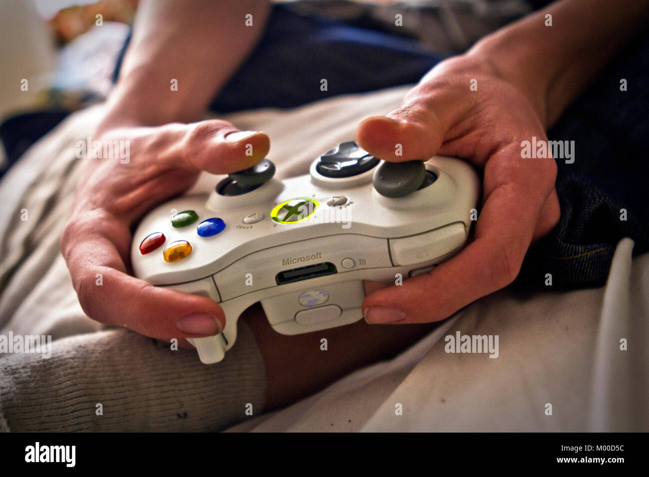 A young man plays a video game with his hands on a Xbox controller from ...