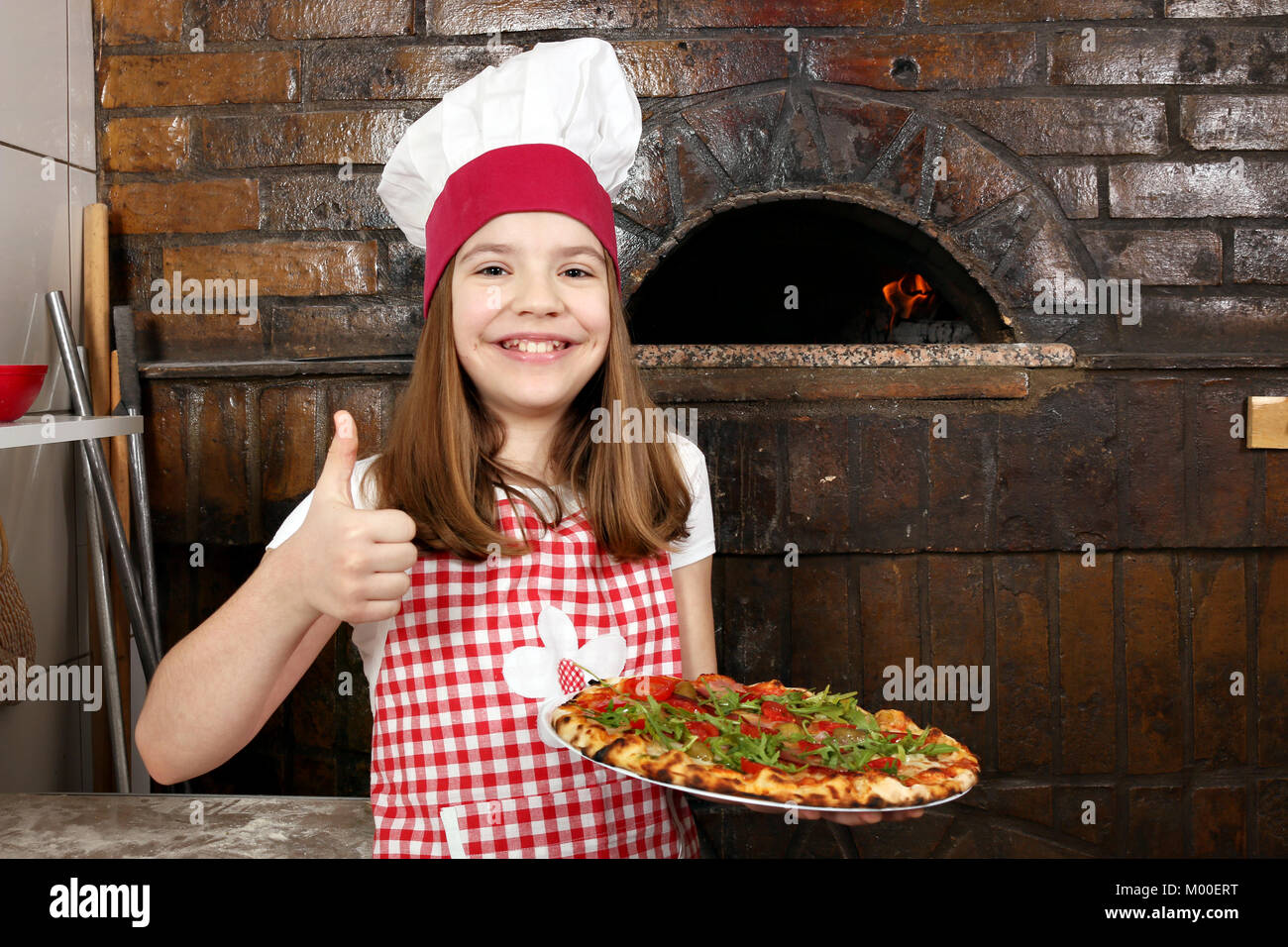 happy little girl cook with pizza and thumb up in pizzeria Stock Photo ...