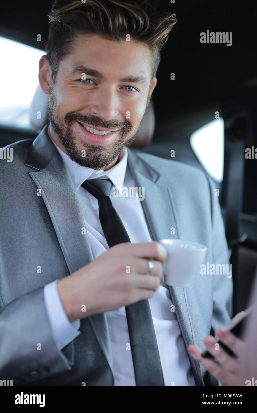 Businessman drinking coffee in the back seat of a car Stock Photo - Alamy