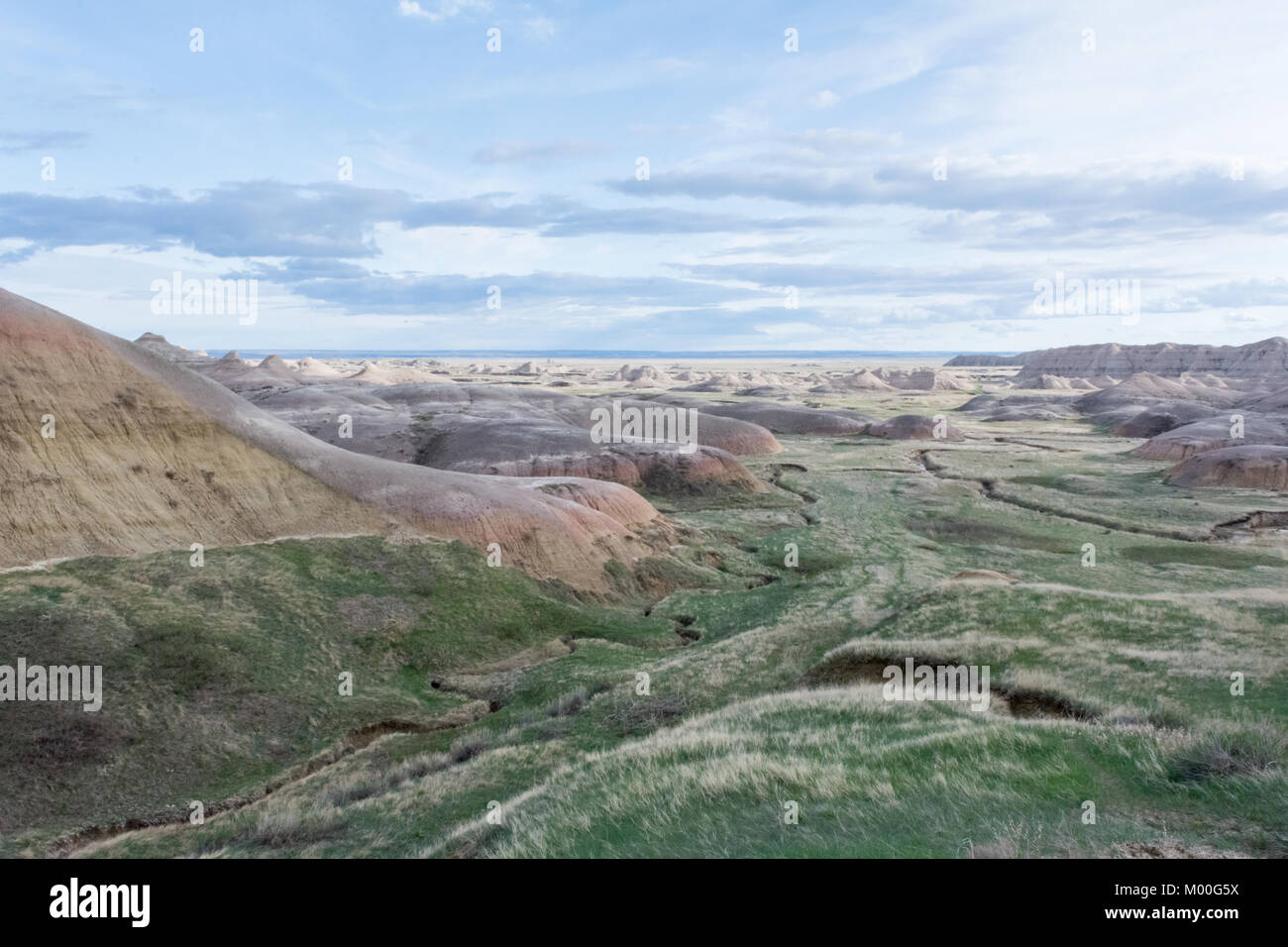 A flat valley is filled with plains grass with sandstone hills on ...