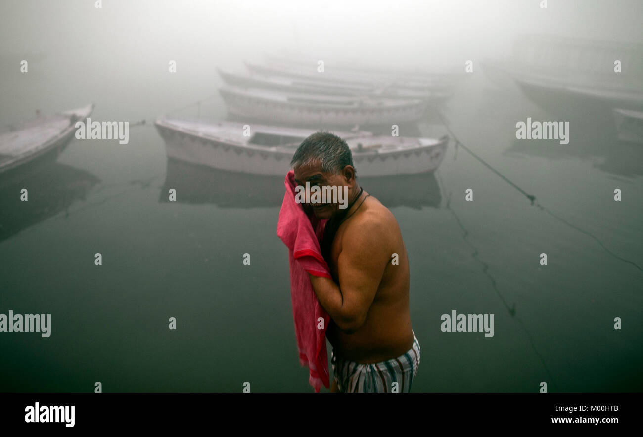 A man is drying his body after a swim in the holy Ganges river. In the ...
