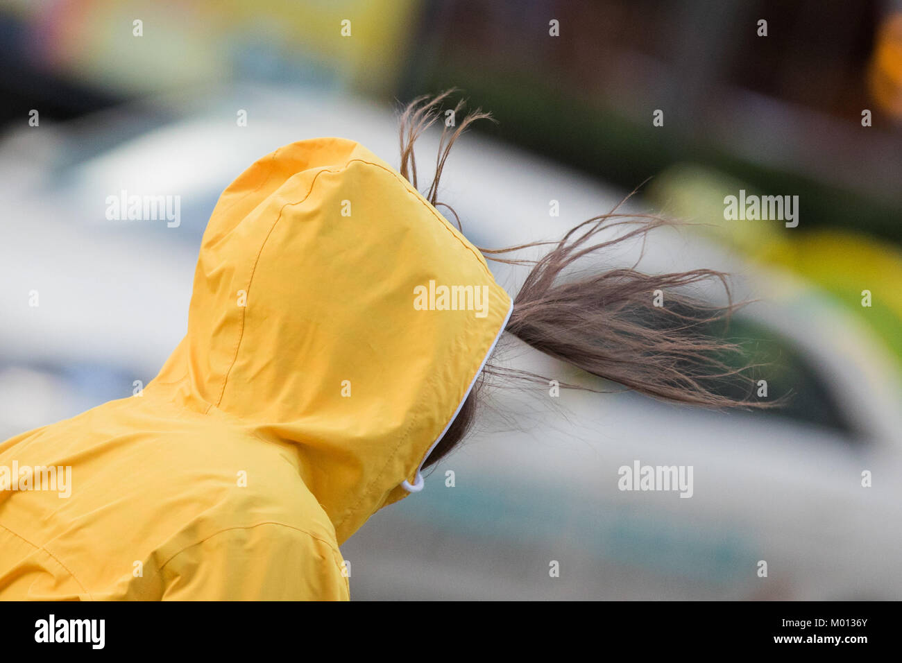 A woman walks around in a rain cape, hair blowing in the wind in ...
