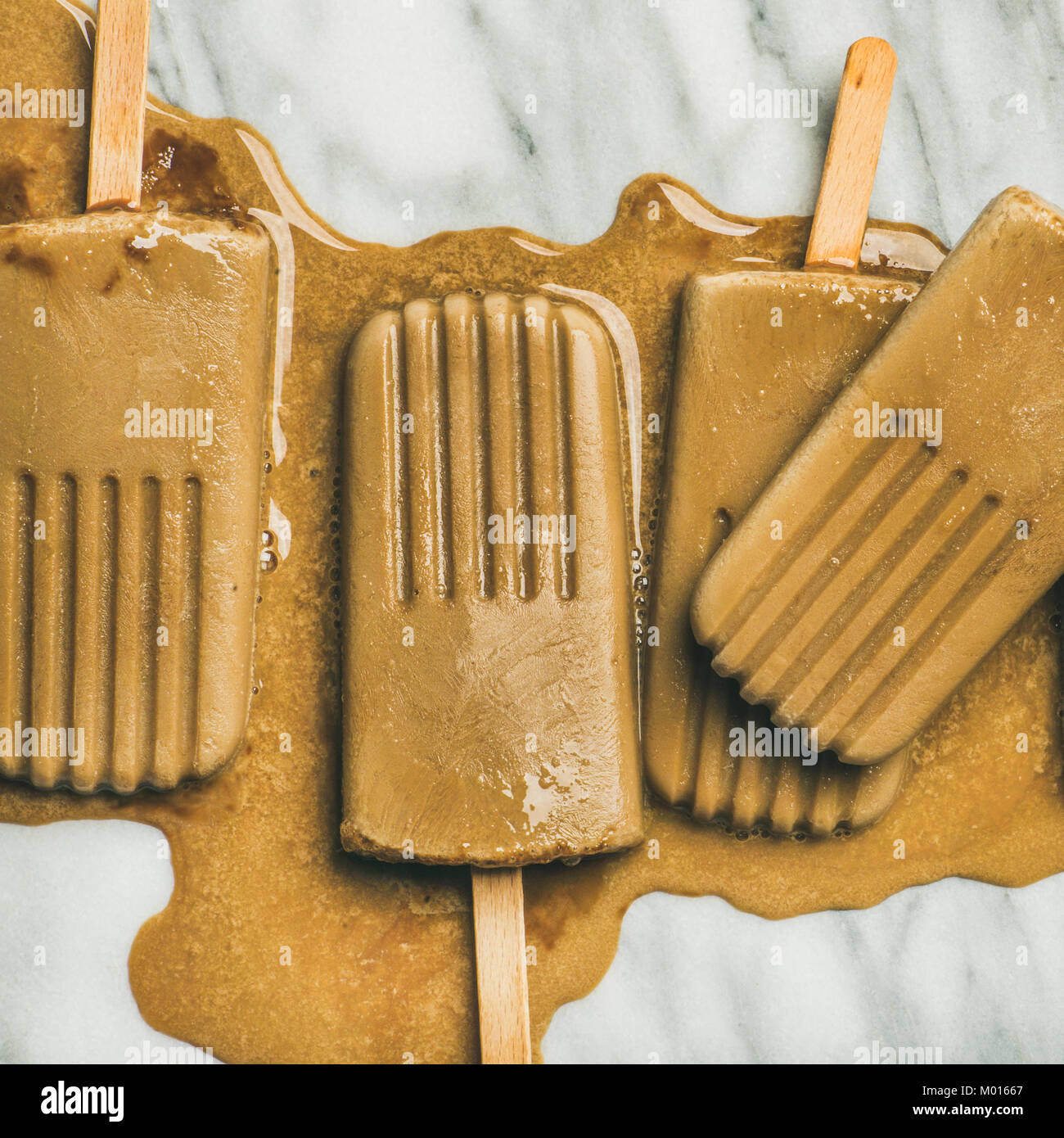 Flatlay of melting coffee latte popsicles on grey marble background ...
