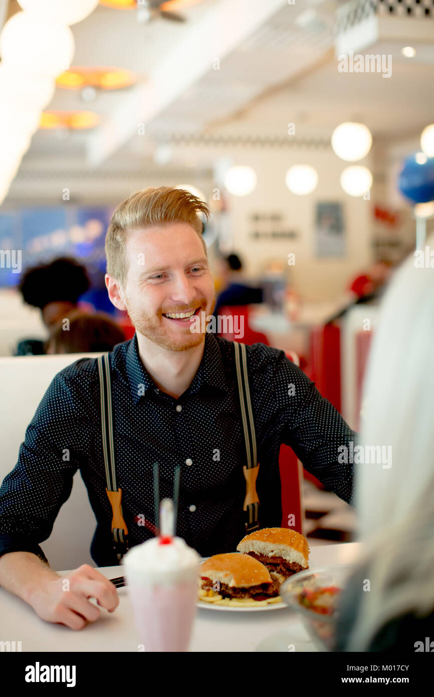 Young man eating beef cheeseburger in diner Stock Photo - Alamy