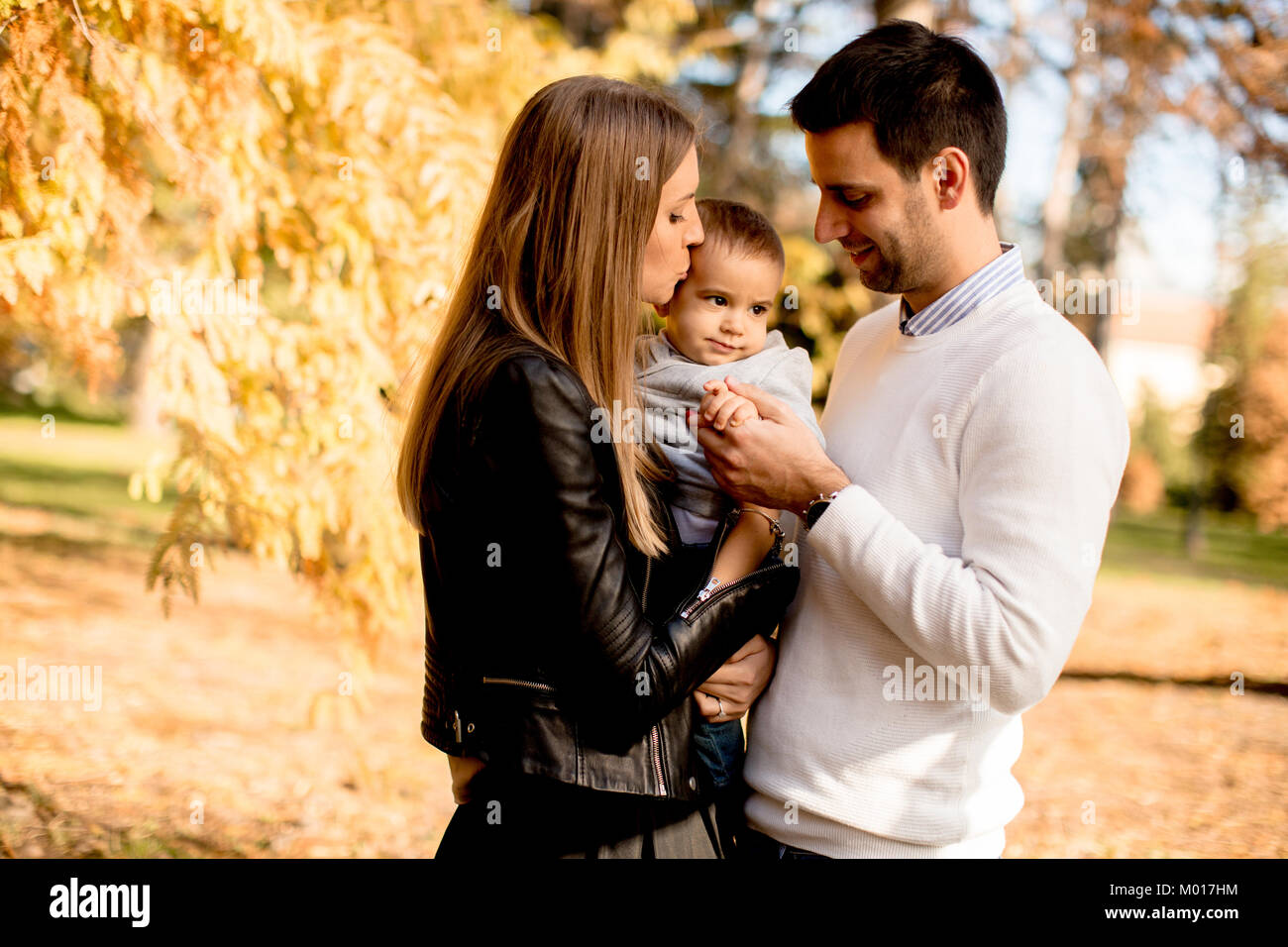 Happy young parents have fun with baby boy in autumn park Stock Photo ...