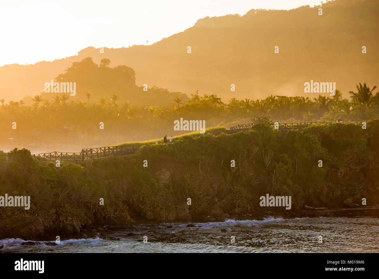 Tourists walk an oceanside path at dawn in the Dominican Republic Stock ...