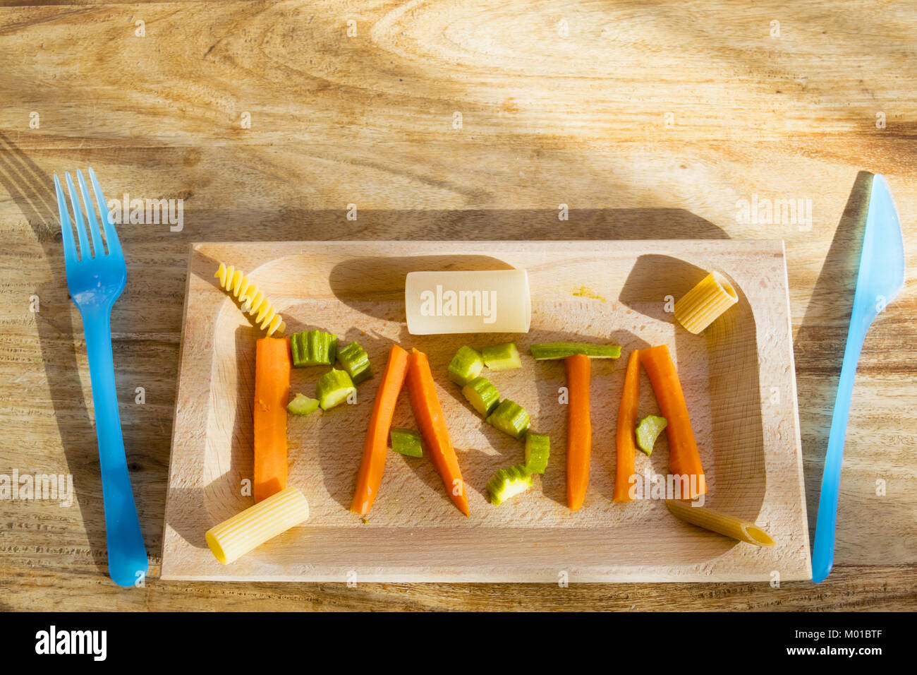 composition of pasta written with variety of vegetables and raw pasta ...