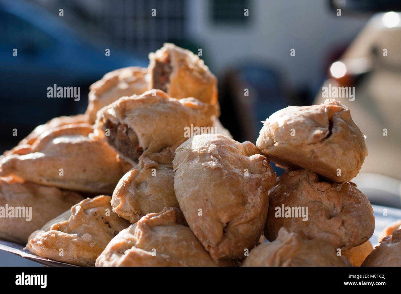 Piled up Cornish pasties and sausage rolls on a street market stall ...