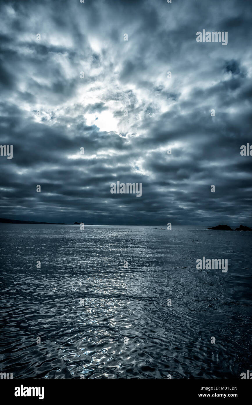 A dreary cloudscape over the ocean diffuses the sunlight as it reflects ...