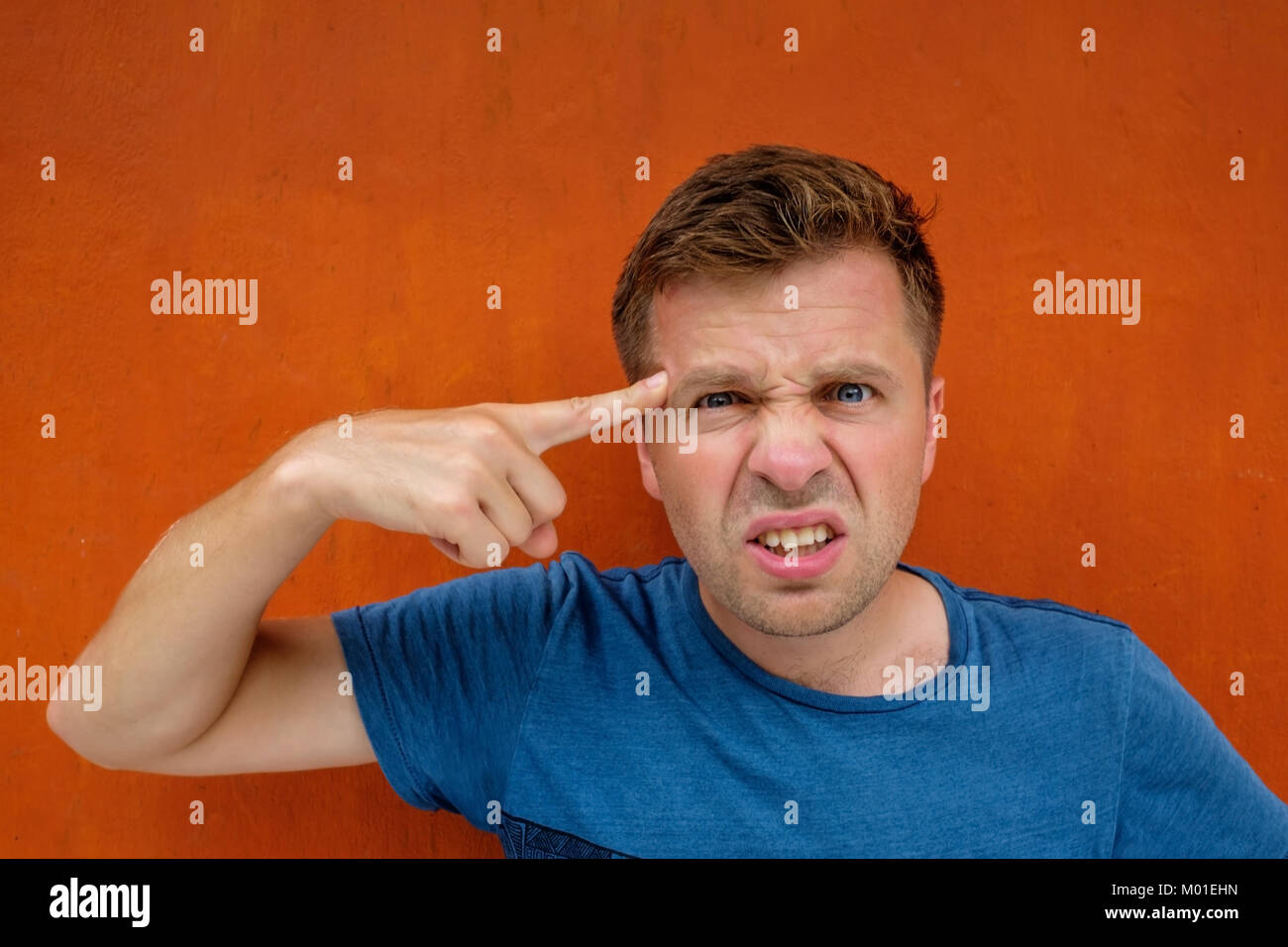 Portrait stressed man with index finger gun gesture near the head on ...