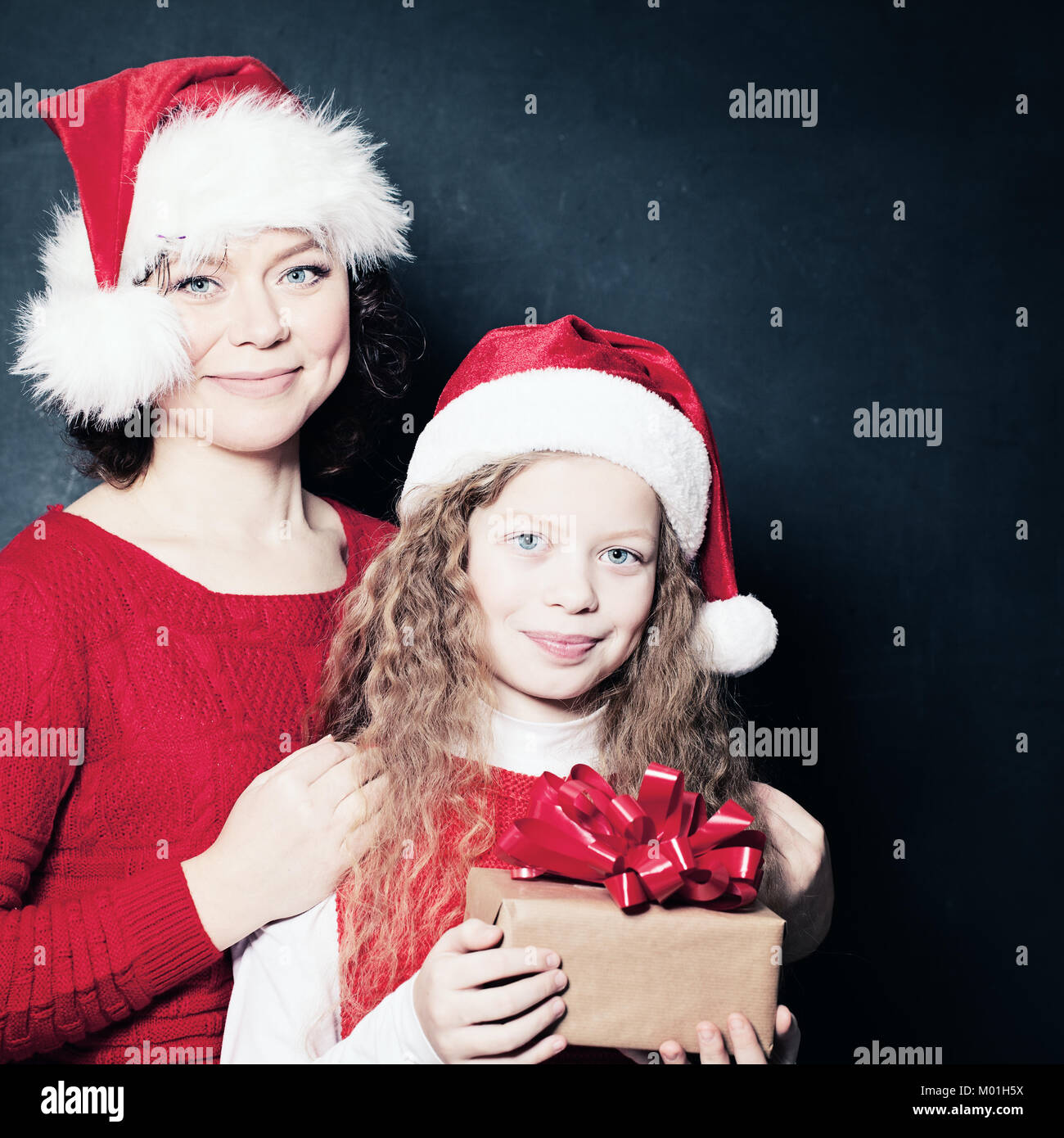 Happy Mother and Daughter in Santa Hat holding Christmas Gift Stock ...