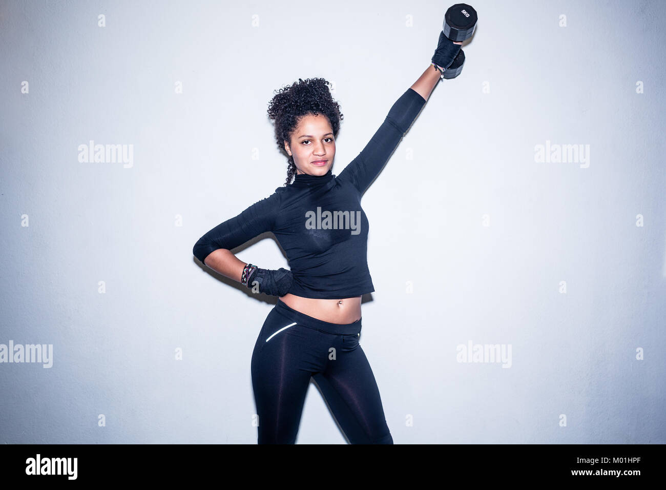 Portrait of young fit woman looking at camera while holding up a Stock ...