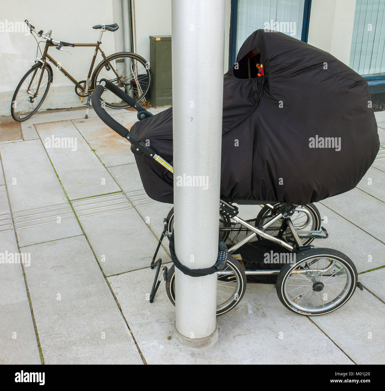 pram ,buggy padlocked to street post, next to bike, Aarhus Denmark ...