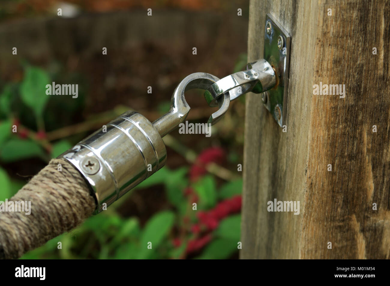 A close up image showing a metal hook and eye fixed to a wooden post ...