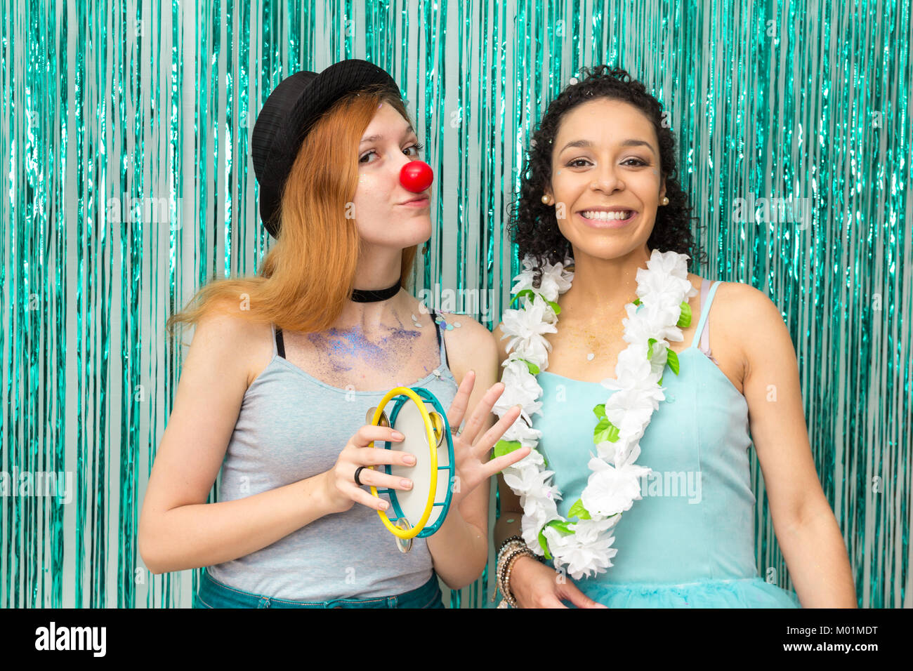 Two friends have fun at Carnaval. One is wearing clown nose and the ...