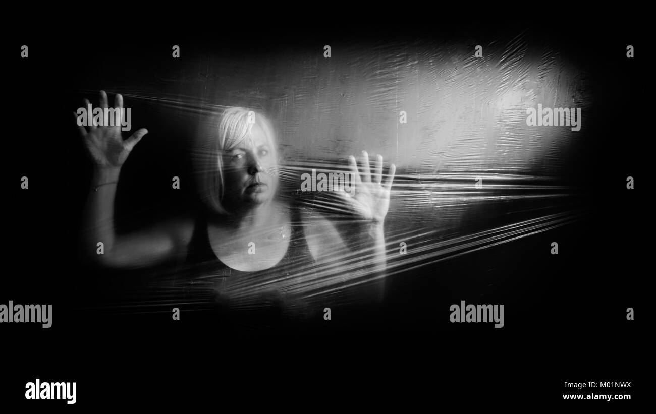 A black and white, low key studio shoot of a woman model trapped behind ...