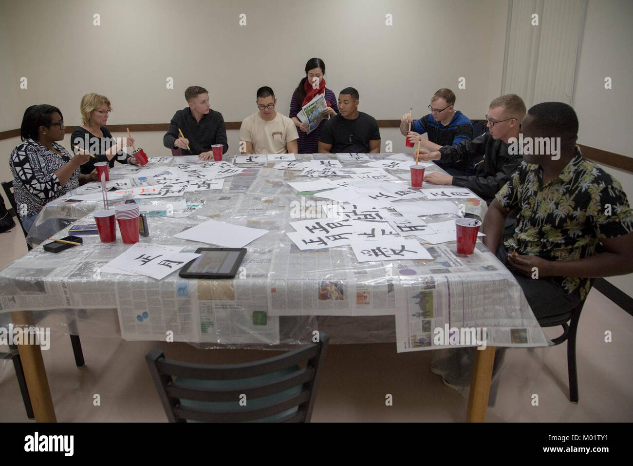 CAMP HANSEN, OKINAWA, Japan – Students sit around a table practicing ...