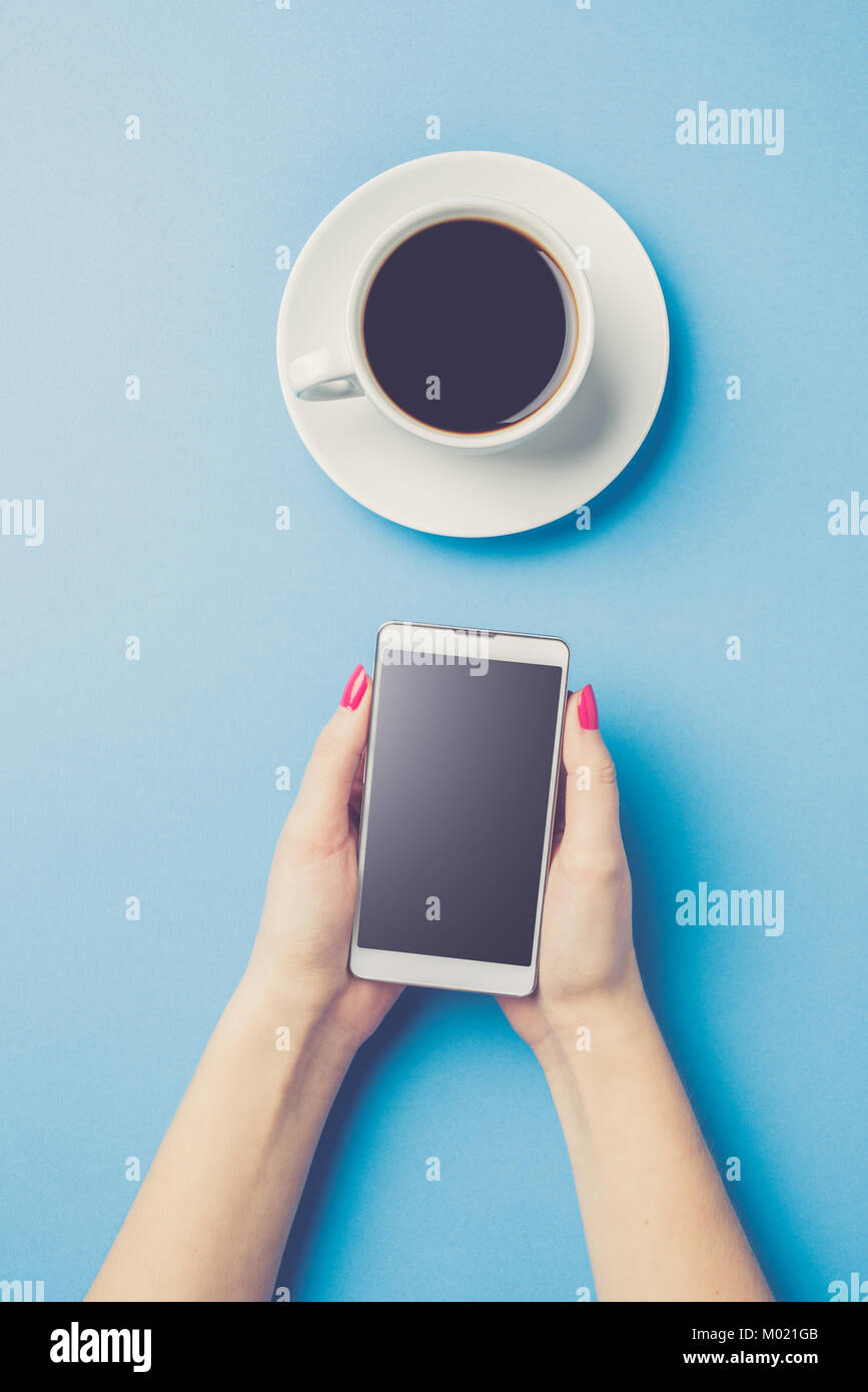 Woman holding phone and drinking coffee. Top view Stock Photo - Alamy