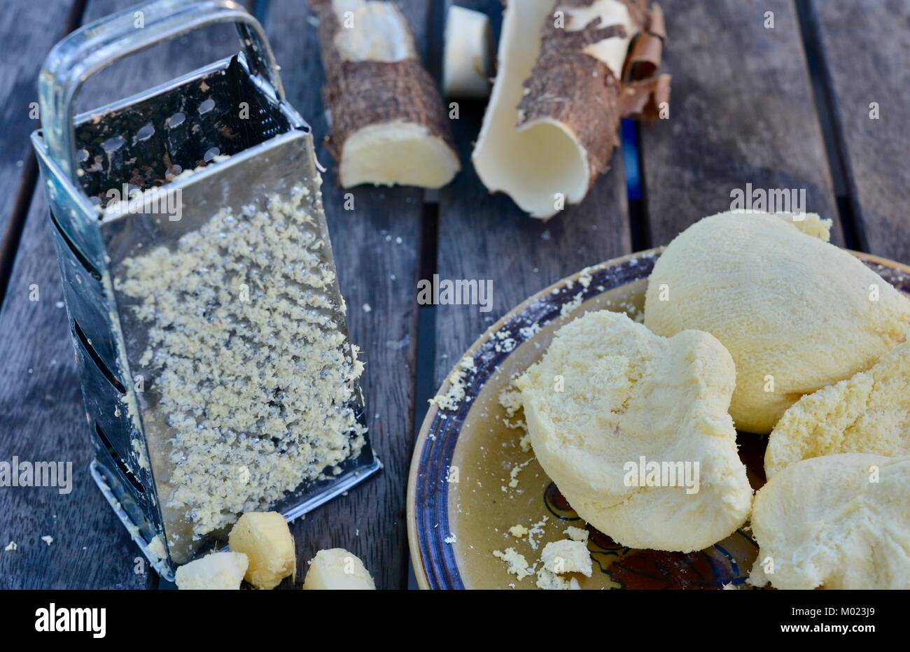 Grating fresh home grown organic cassava to prepare cassava bread ...