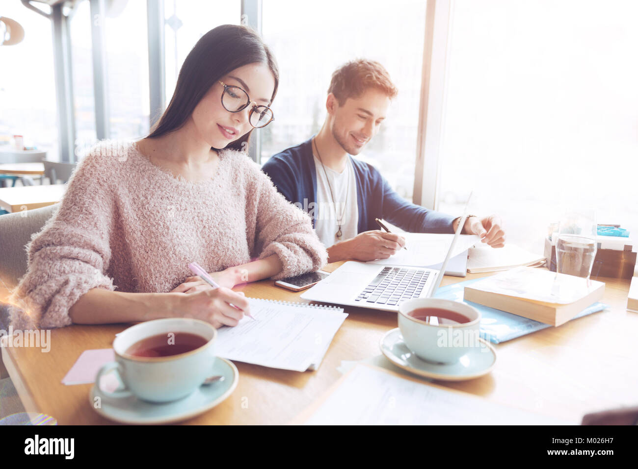 Beautiful female bowing head while making notes Stock Photo - Alamy