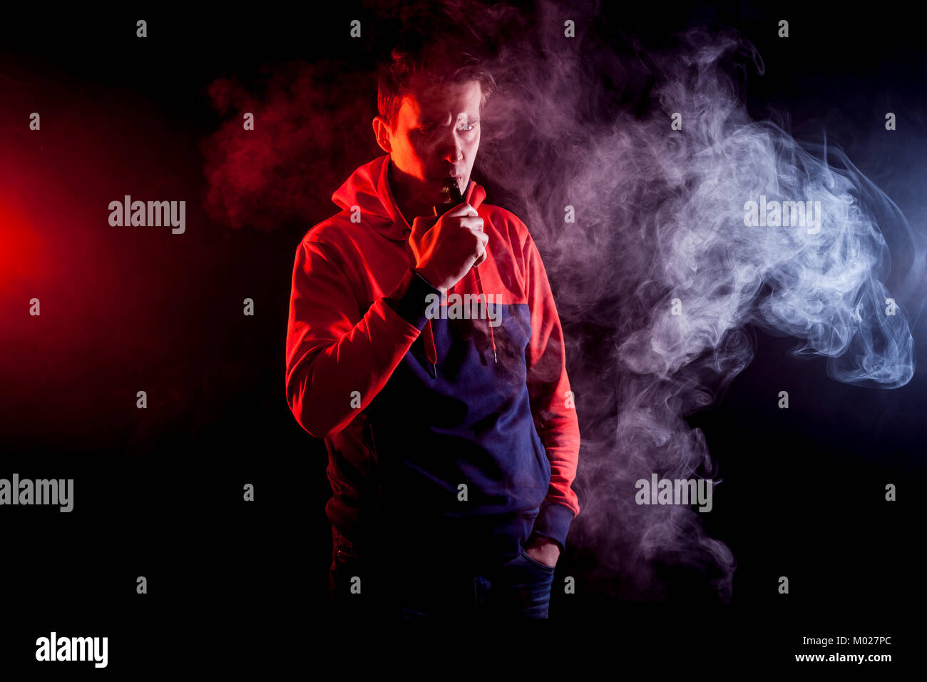 vaping man holding a mod. A cloud of vapor. Black background Stock ...