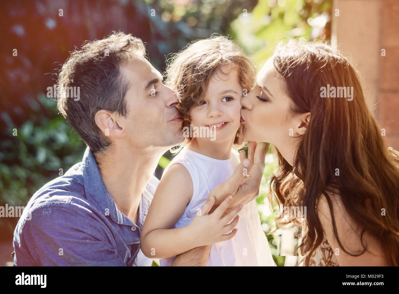 Happy parents kissing their beloved daughter Stock Photo - Alamy