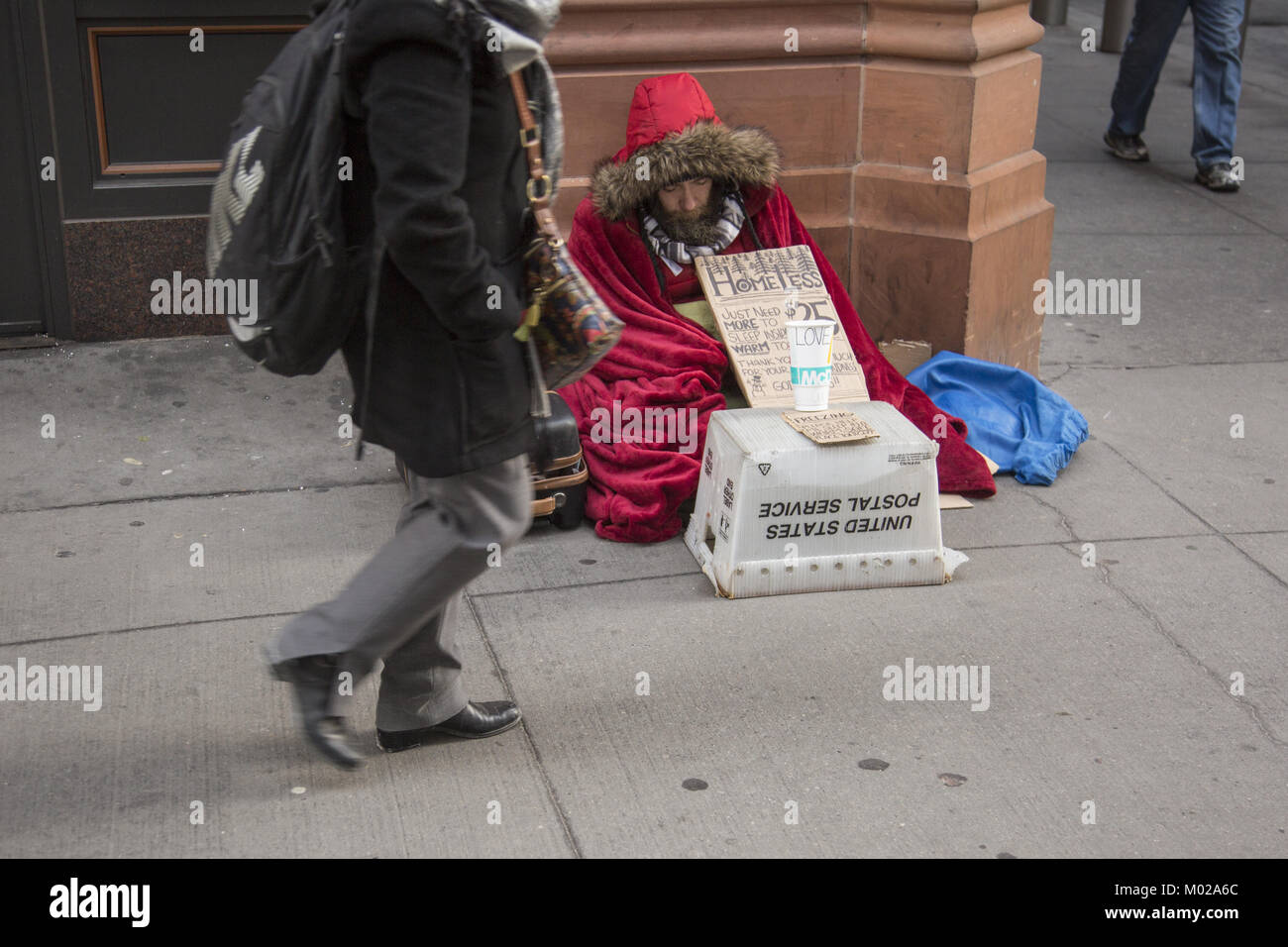 Homeless man sits bundled up on a very cold winter day asking for help ...