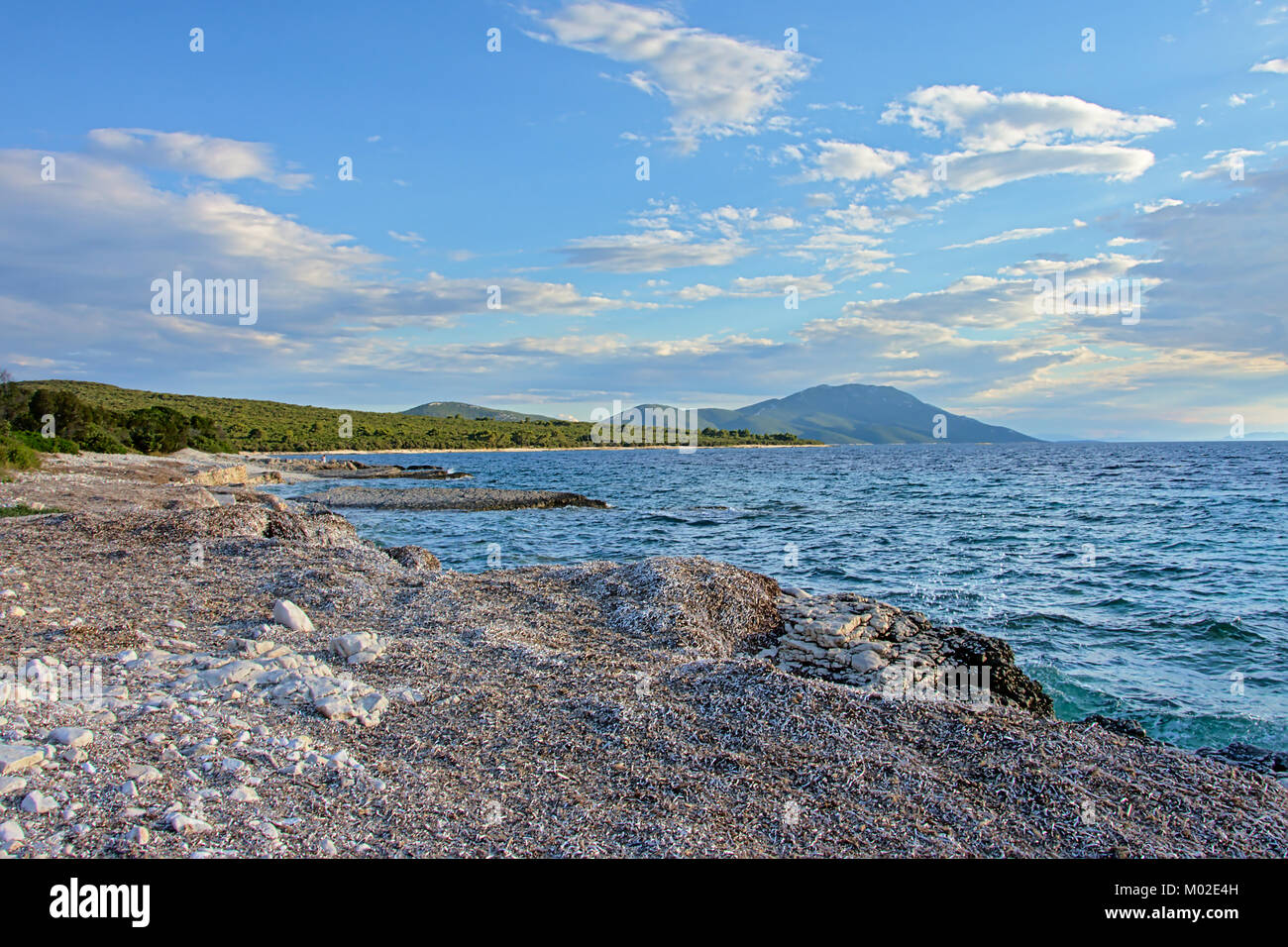 Rock beach of the adriatic with mountains in the distance on a su Stock ...