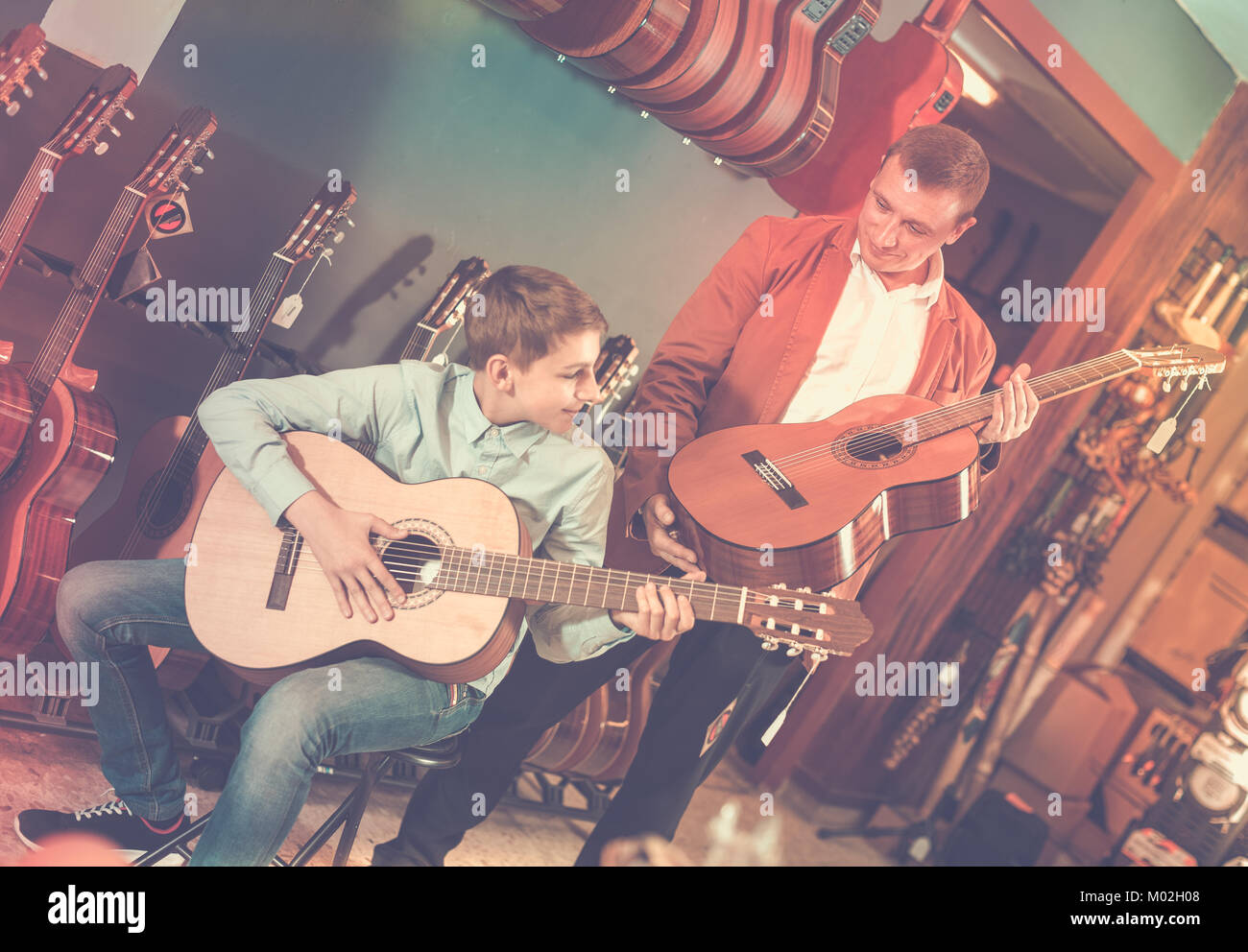 Positive young boy and father choosing best acoustic guitar in musical ...