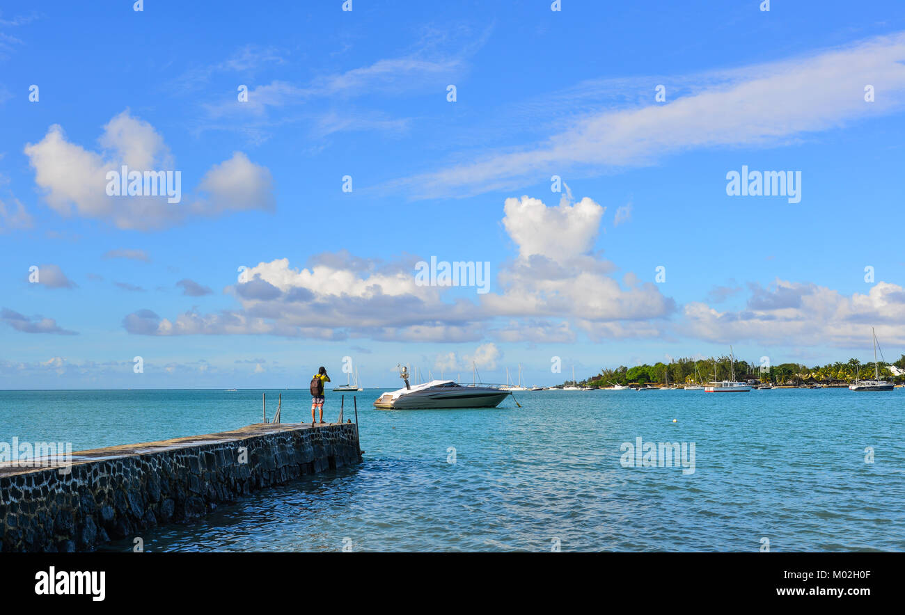 A man standing on jetty bridge and taking pictures in Grand Baie ...