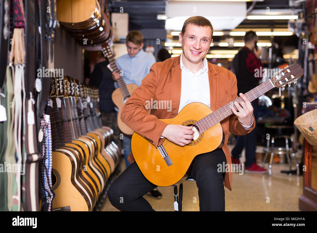 Smiling russian male customer deciding on acoustic guitar in musical ...