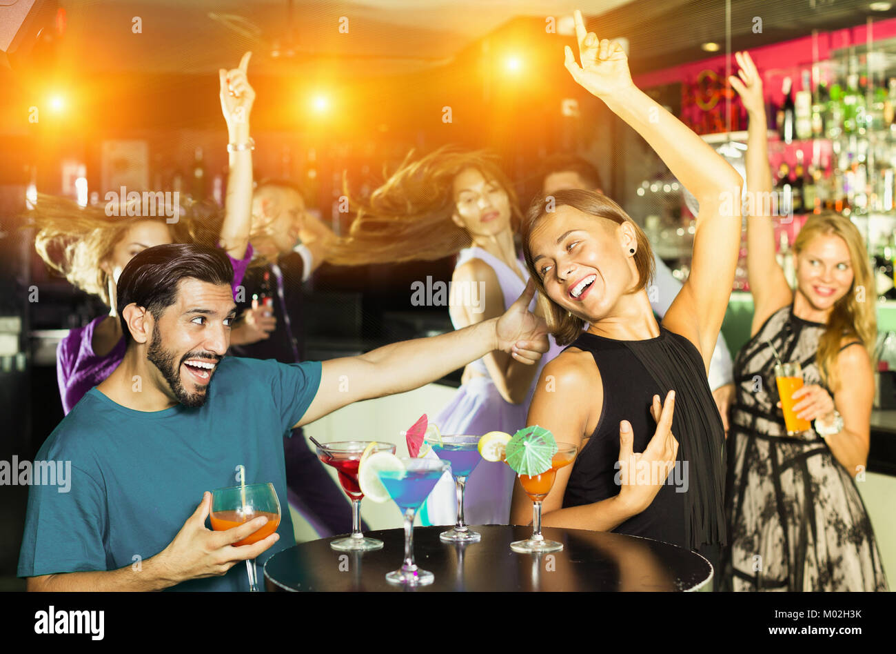 Young woman with man are dancing and drinking cocktail on the party in ...