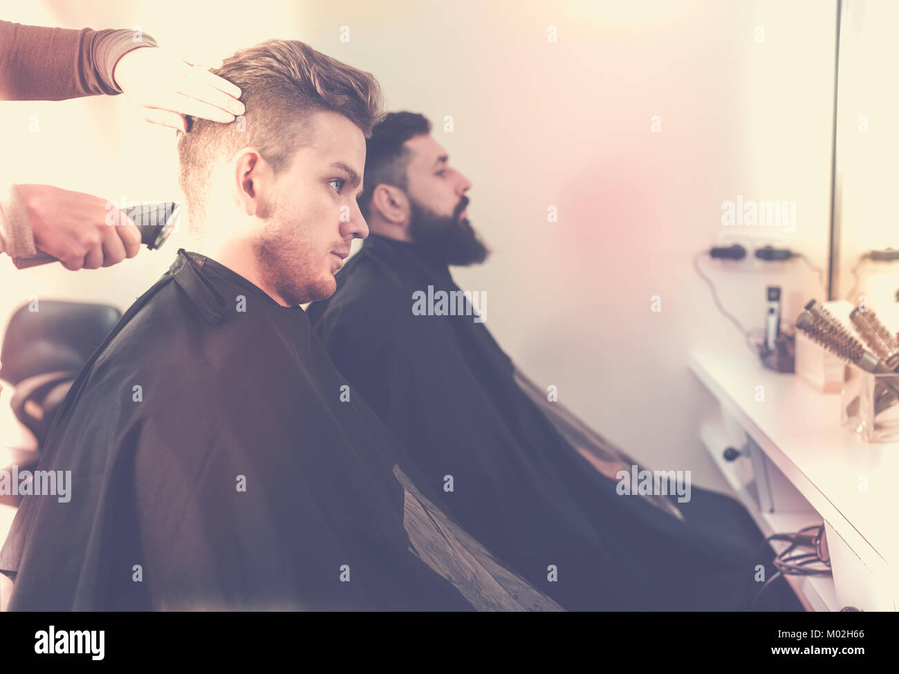 Happy men having their hair cut by hairdressers at hair salon Stock ...